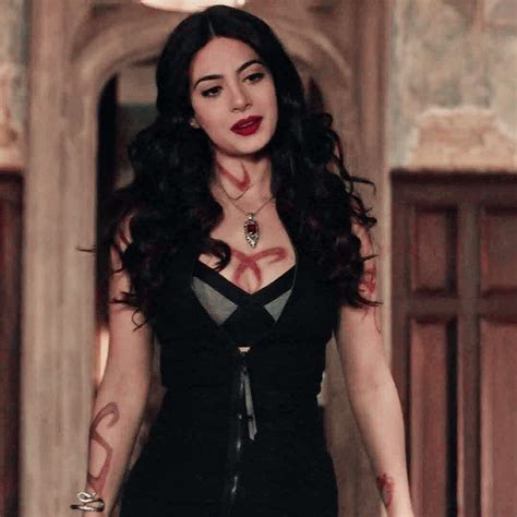 A Woman With Long Black Hair And Tattoos On Her Chest Is Walking Down A Hallway