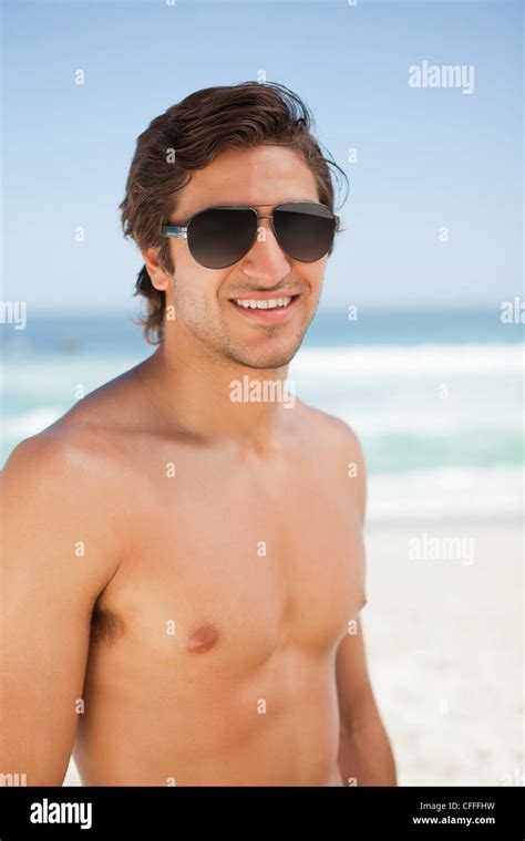 Smiling Handsome Man Standing On The Beach While Wearing Sunglasses