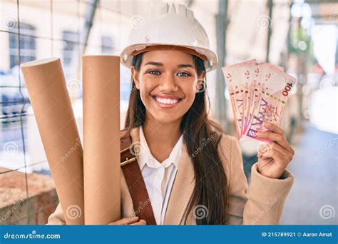 Young Latin Architect Girl Smiling Happy Holding Blueprints And Hong