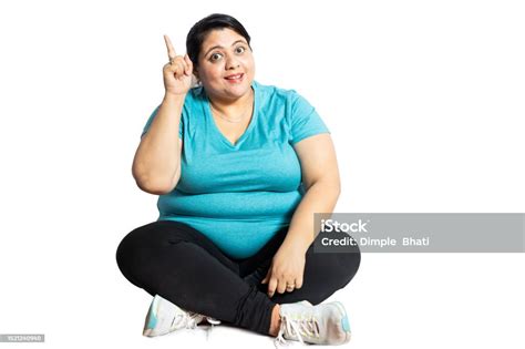 하얀 스튜디오 배경 위에 고립된 바닥에 앉아 있는 그녀의 얼굴에 아이디어 표현을 하는 과체중 인도 여성 비만증에 대한 스톡 사진 및 기타 이미지 Istock