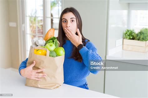 건강 한 식료품을 들고 아름 다운 젊은 여자는 실수로 두려움의 표현 침묵에 무서 워 비밀 개념에 대 한 수치와 충격을 손으로 입을 커버 가득 찬에 대한 스톡 사진 및 기타