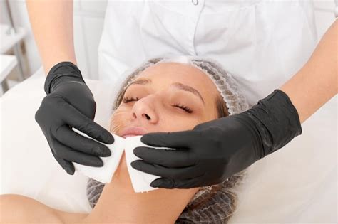 Premium Photo Beautician Removing Facial Cream Mask From Woman Face Skin With Cosmetic Wipes