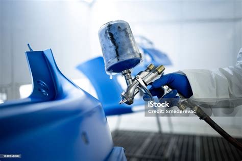 보호복을 입은 자동차 화가와 챔버 워크샵에서 금속 페인트와 니스로 자동차 범퍼를 그림으로 그린 자동차 화가 차에 대한 스톡 사진