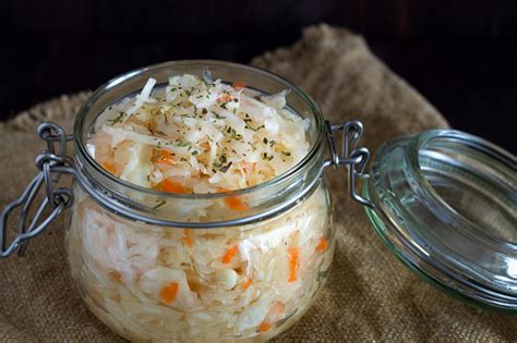 검은 색 배경에 유리 항아리에 허브와 당근과 클로즈업 홈 메이드 소금에 절인 양배추 나무 테이블에 자루가 있는 양배추절임 통조림