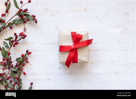 One Christmas Parcel Tied With A Red Ribbon Bow On A White Wood