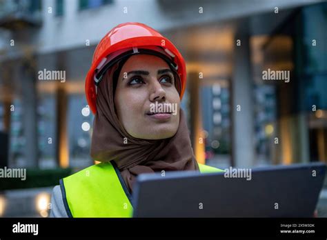 Uk London Female Engineer In Hijab And Hardhat Using Digital Tablet