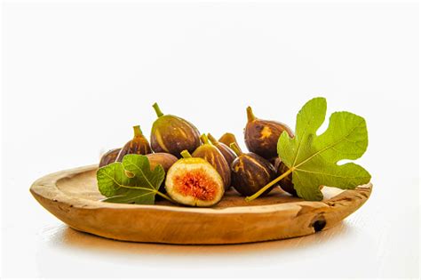 신선한 생 무화과 과일과 흰색 배경에 고립 된 나무 접시에 테이블 위에 부분과 무화과 잎을 자릅니다 복사 공간이 있는 제품 템플릿의 정물 수명 0명에 대한 스톡 사진 및