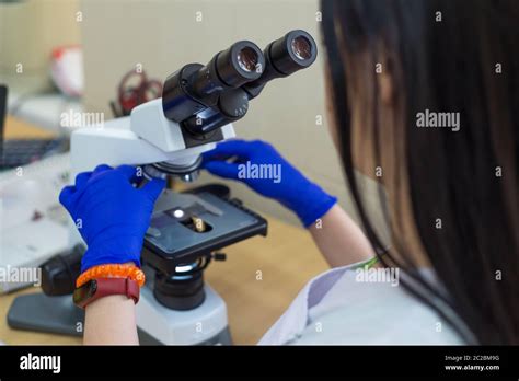 Scientist Conducting Research Taking Notes Whilst Looking Through Microscope Selective Focus