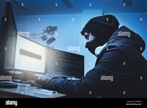 Side View Of A Hacker Breaking Into Corporate Data Servers From His Underground Hideout Stock