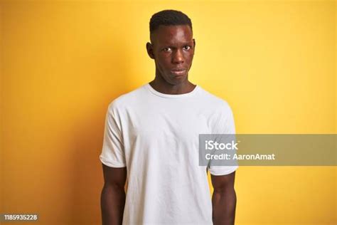 고립된 노란색 배경에 서 흰색 티셔츠를 입은 젊은 아프리카 계 미국인 남성이 문제 때문에 화가 났습니다 부정적인 사람 T 셔츠에 대한 스톡 사진 및 기타 이미지 Istock
