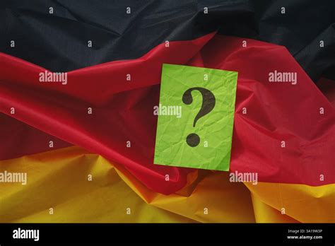 a green paper note with a question mark on it lying on the german flag