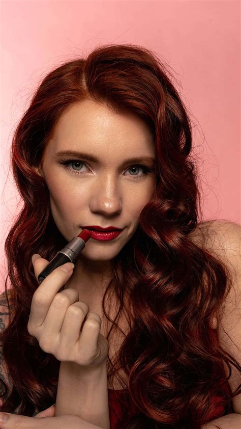 Download Redhead Applying Lipstick Aesthetic Wallpaper