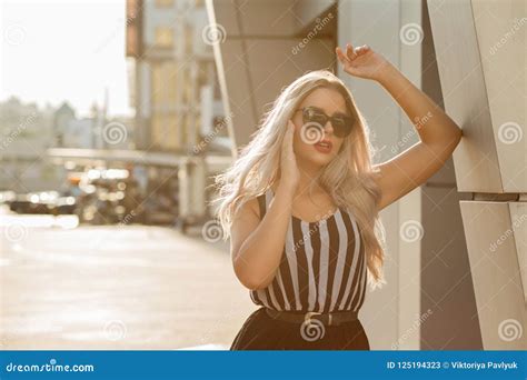 Seductive Blonde Girl Wearing Sunglasses Walking Down The Street With