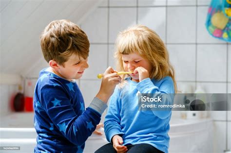 작은 유치원 소녀와 십대 학교 소년 양치질 치아 동생 은 양치질을 가르치는 형제 슬픈 화가 우는 아이 두 아이와 아침 치과 루틴 실내가족 아이에 대한 스톡 사진 및 기타