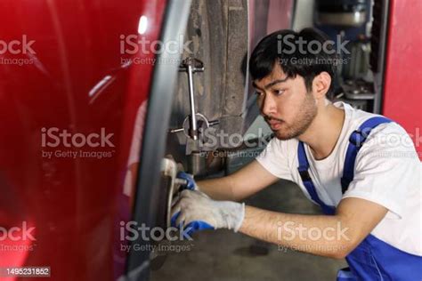남자 기술자 자동차 정비사는 제복을 입고 수리 차고 역에서 리프트 자동차 서비스를 점검하거나 유지 보수합니다 렌치를 잡고 브레이크 디스크를 고정하는 작업자 자동차 센터 수리
