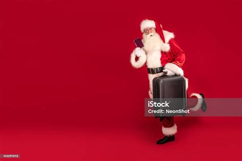 흰 머리카락 수염 여행 가방과 여권을 손에 들고 달리는 진짜 산타 클로스의 전체 길이 사진 크리스마스 시간 레드 스튜디오 배경 12월에 대한 스톡 사진 및 기타 이미지
