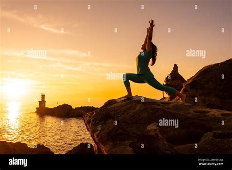 Anjaneyasana A Woman Doing Meditation And Yoga Exercises On A Rock At