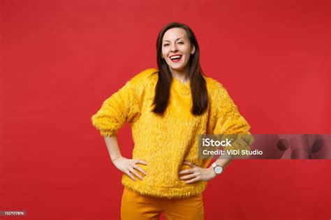 팔 두 스튜디오에서 밝은 빨간 벽 배경에 고립 된 노란색 모피 스웨터 서에서 웃는 예쁜 젊은 여자의 초상화 사람들이 진심으 감정
