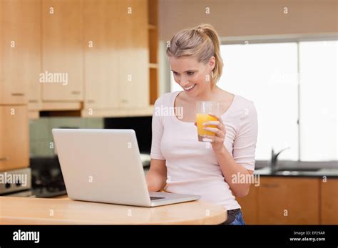 Woman Using A Laptop While Drinking Juice Stock Photo Alamy