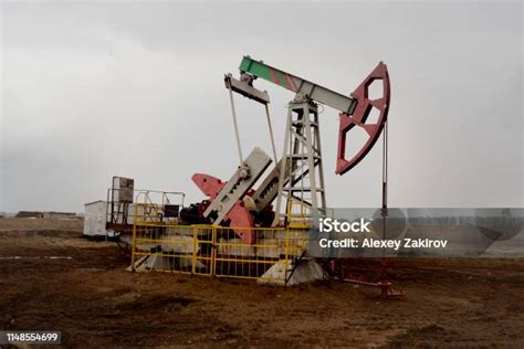 빔 펌핑 유닛은 숙제 오일 필드의 일몰입니다 석유 펌프 오일 장비 에너지 산업 기계 펌프가 우물에 설치 된 펌핑 장치 오일 분야의 장비 강철에 대한 스톡 사진 및 기타