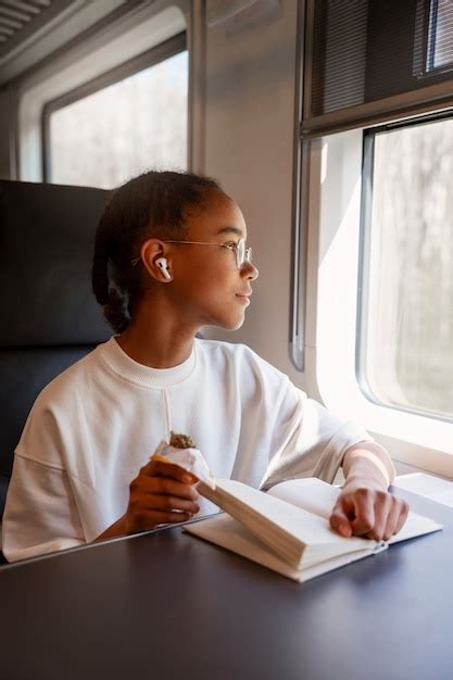 Coup Moyen Fille Avec Livre Dans Le Train Photo Gratuite
