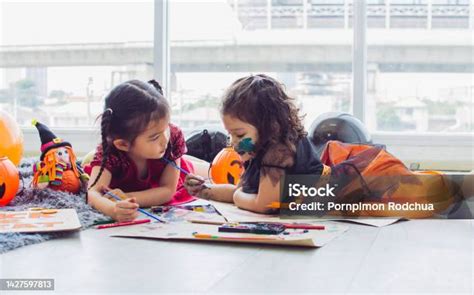 할로윈 파티를 축하하기 위해 마녀 의상을 입은 두 개의 작은 귀여운 백인 아시아 소녀 그림 행복 재미와 함께 거실바닥에 누워있는 동안 함께 그림 10월에 대한 스톡 사진 및