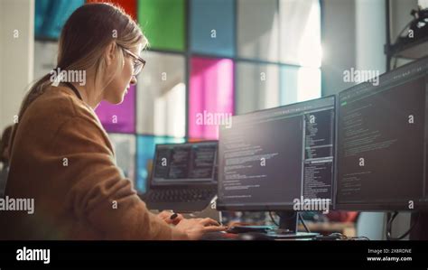 Female Software Engineer Writing Lines Of Code On Professional Multiple Display Pc Setup In