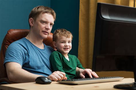 아버지와 작은 아들 집에서 컴퓨터를 사용 하 여입니다 아들과 함께 아버지 비디오를 시청 하 고 유쾌 하 게 함께 시간을 보내고