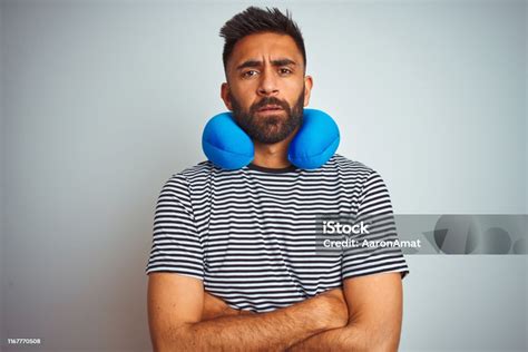 고립 된 흰색 배경 회의적이고 긴장한 얼굴에서 교차 된 팔로 표정을 거부하는 목 베개를 착용한 여행에 젊은 인도 관광객 남자 부정적인 사람 감정에 대한 스톡 사진 및 기타