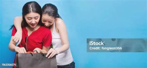 쇼핑 개념으로 두 아름다운 아시아 미소 젊은 여성의 초상화 매력적인 미소와 쇼핑 백을 들고 여자 파란색 배경에 격리됩니다 복사 공간이 있는 배너 배경 소매 소비자주의에 대한