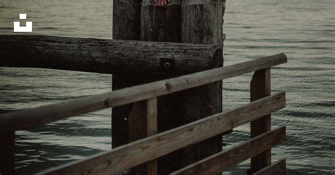 남자와 여자가 수역 근처의 기둥에 앉아서 키스하고 있습니다 사진 Unsplash의 무료 사랑 이미지