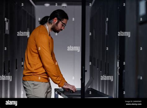 Minimal Side View Portrait Of Bearded Network Engineer Using Laptop In