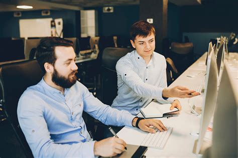 노트북에서 Office 프로젝트에서 작업 하는 동안 그래픽 태블릿와 동료에 대 한 컴퓨터 모니터에서 가리키는 젊은 남자 디자인 프로젝트에 함께 일 하는 동료 가리키기에 대한