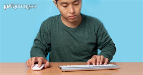 Young Man Using Wireless Mouse And Keyboard Typing On Keyboard Working Isolated On Blue