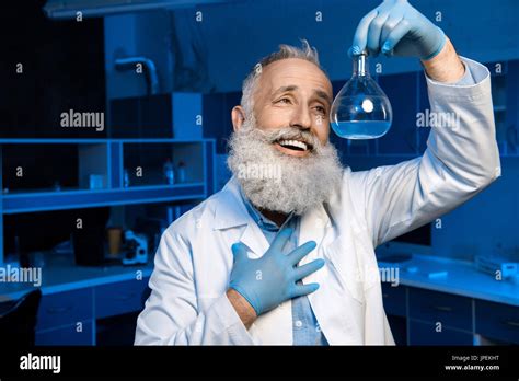 Happy Grey Haired Scientist In Lab Coat Holding Flask With Reagent