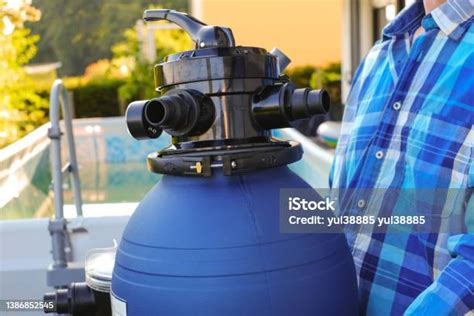 수영장 필터 수영장 청소 장비 파란색 수영장 배경에 격자 무늬 셔츠를 입은 남자의 손에 파란색 물 필터 한 남자가 호스를 풀의 필터로 이동합니다 깨끗한에 대한 스톡 사진 및