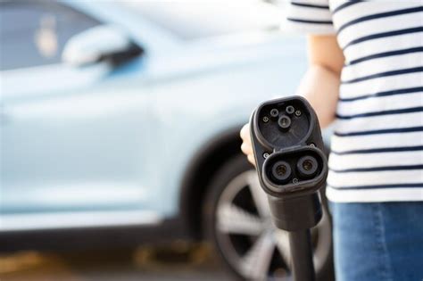 Ev 충전소에서 Dc Ccs 유형 2 Ev 충전 커넥터를 들고 있는 알아볼 수 없는 아시아 여성 충전용 Ev 전기 자동차 충전
