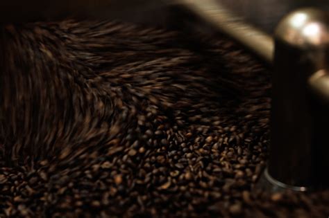 클로즈업 및 저속 셔터가 흐려져 회전 혼합 커피 로스터 스핀 머신 공정에서 움직이는 다크 로스트 커피 원두의 움직임을 포착합니다