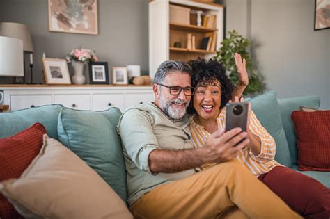 미소 짓는 중년 부부가 거실에서 영상 통화를 하면서 카메라를 향해 직접 손을 흔듭니다 2명에 대한 스톡 사진 및 기타 이미지 2명 Brand Name Smart