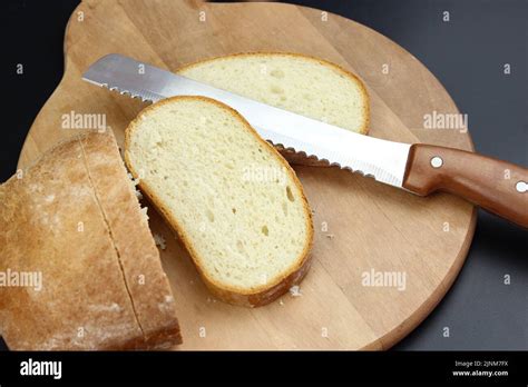 A Large Knife Cuts Thin Pieces Of White Bread From A Rectangular Loaf