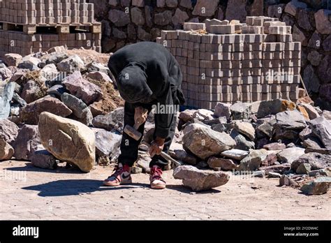 A Stone Mason Shapes A Stone With A Hammer And Chisel At A Construction