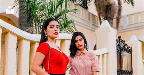 빨간 탱크탑과 파란색 데님 반바지를 입은 여자가 낮 동안 회색 콘크리트 바닥에 서 있다 사진 Unsplash의 무료 의복 이미지