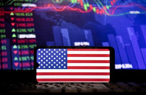 American Flag On The Screen Of A Cell Phone And In The Background Random Stock Market Charts