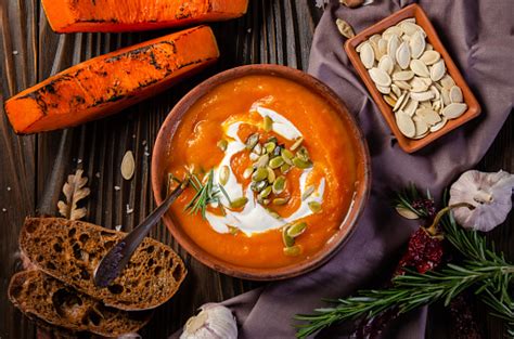 빵 향신료와 채소를 따로 구운 나무 테이블에 점토 접시에 씨앗을 곁들인 홈메이드 소박한 호박 수프의 플랫 레이 뷰 0명에 대한