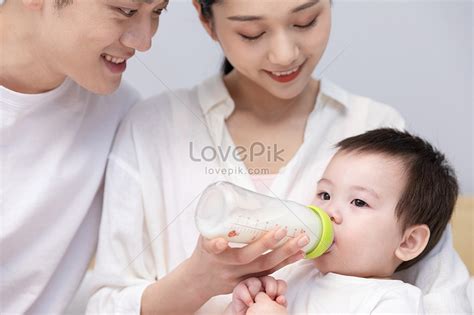 우유를 마시기 위해 아기를 먹이는 세 아버지와 어머니의 가족