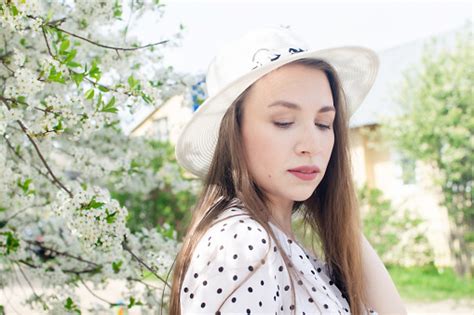 꽃이 만발한 사과와 벚꽃 근처의 공원이나 정원에서 포즈를 취하는 아름다운 소녀 갈색 머리에 대한 스톡 사진 및 기타 이미지 갈색 머리 개념 개화기 Istock