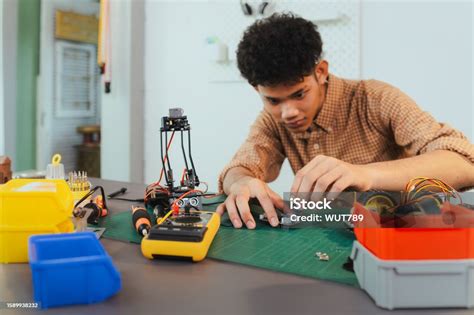 Asian Young Man Assembling A Robotic Car Focus On Robotics Assembling A