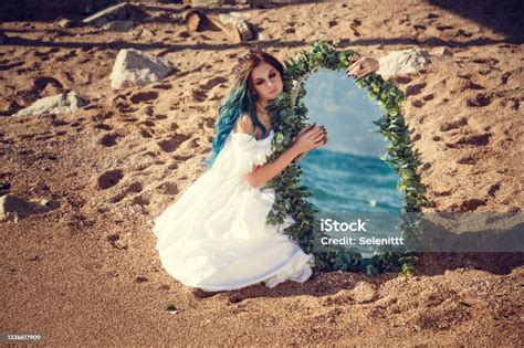 푸른 머리와 흰색 빈티지 드레스와 아름다운 소녀는 바다를 본다 그녀의 손에 바다가 반사되는 아름다운 골동품 거울 책 표지 25 29세에 대한 스톡 사진 및 기타 이미지