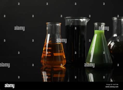 Glass Flasks And Beaker With Different Types Of Oil On Black Background