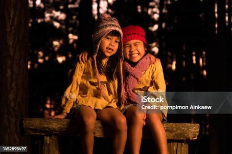 귀여운 여동생들은 추운 날씨에 야외 모닥불 근처에서 따뜻합니다 캠프 파이어에서 즐거운 시간을 보내는 아이들 겨울 소나무 숲에서 아이들과 캠핑 자연 속에서 휴가를 보내는